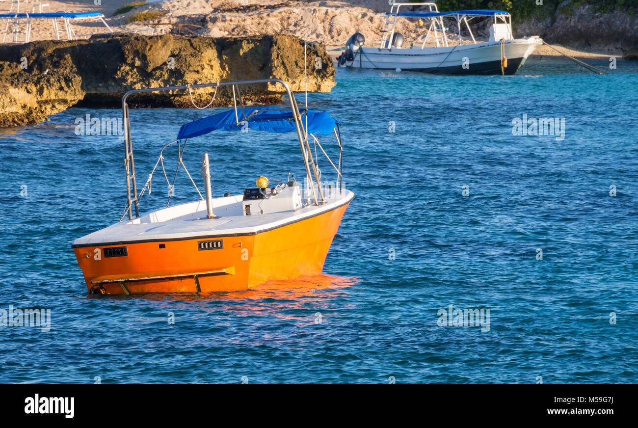 Small bright orange fishing boat, tourist boat at a tropical island ...