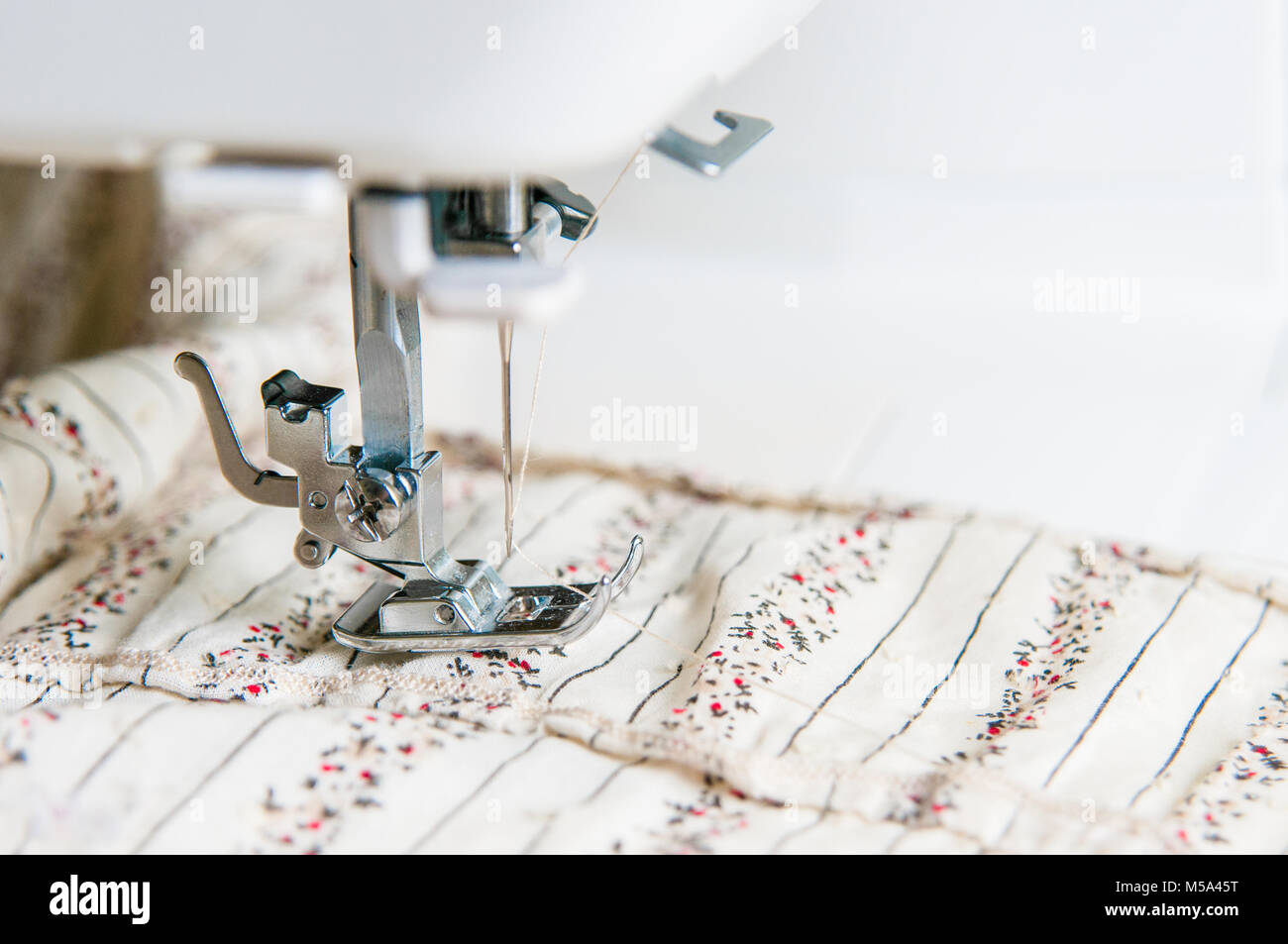 Modern Sewing machine with light flower pattern fabric Stock Photo - Alamy