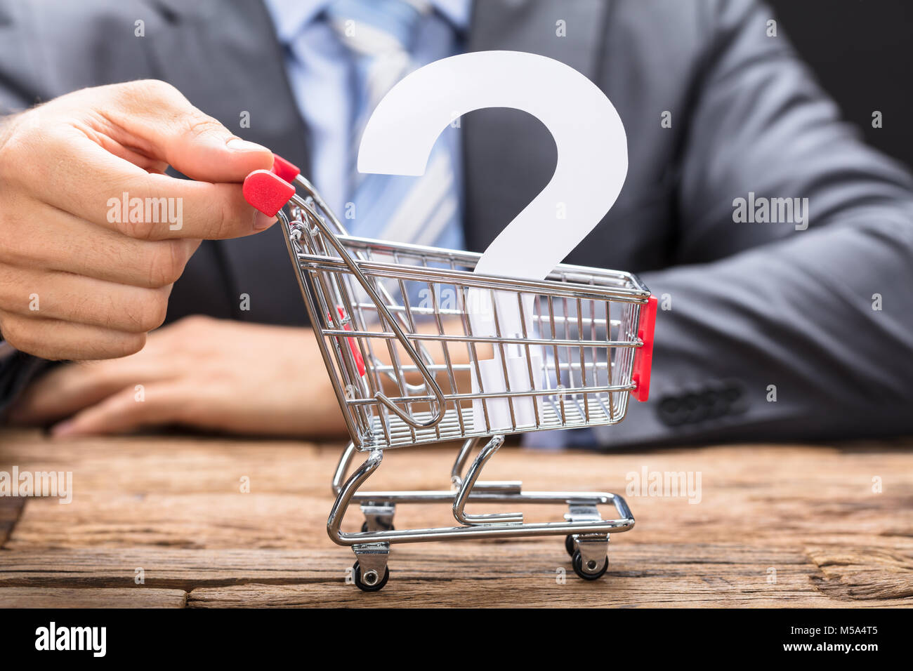 Midsection of businessman pushing question mark in shopping cart on ...