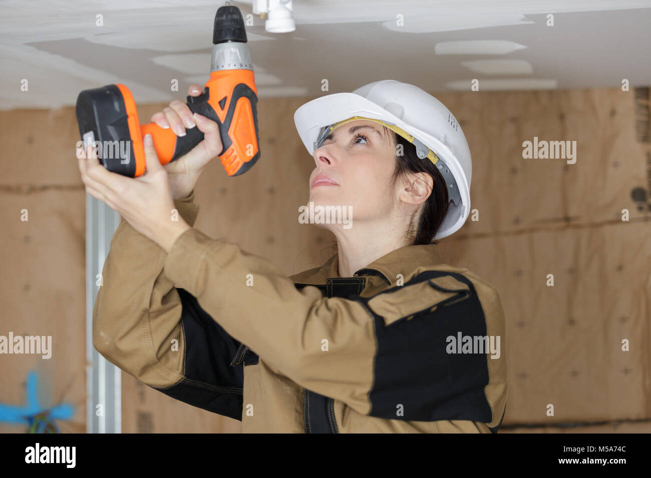 Female contractor drilling into ceiling Stock Photo - Alamy