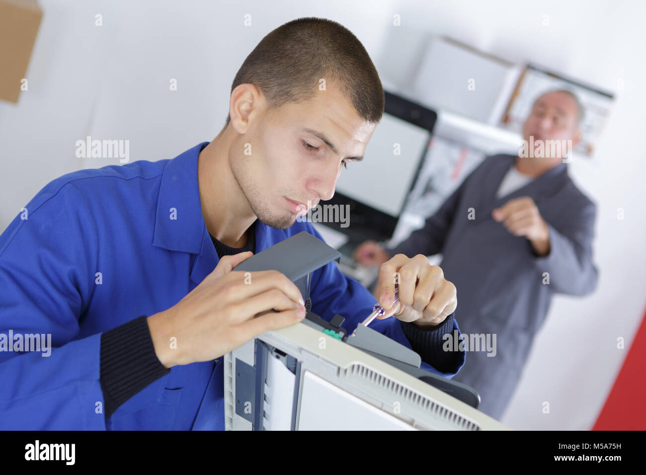 young man fixing a printing machine Stock Photo - Alamy