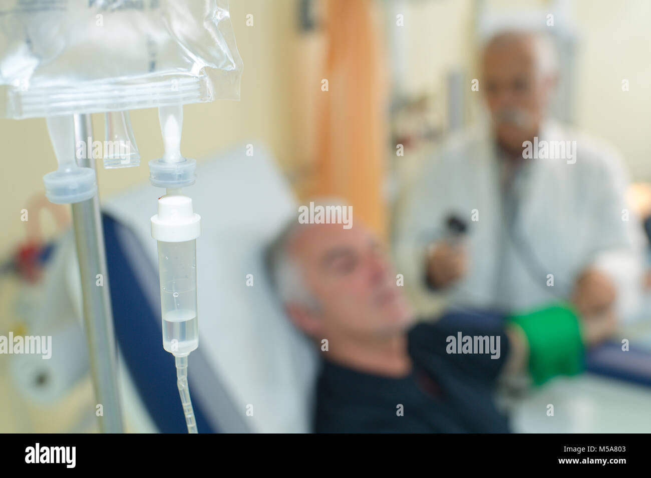 Closeup of saline drip, patient in background Stock Photo - Alamy