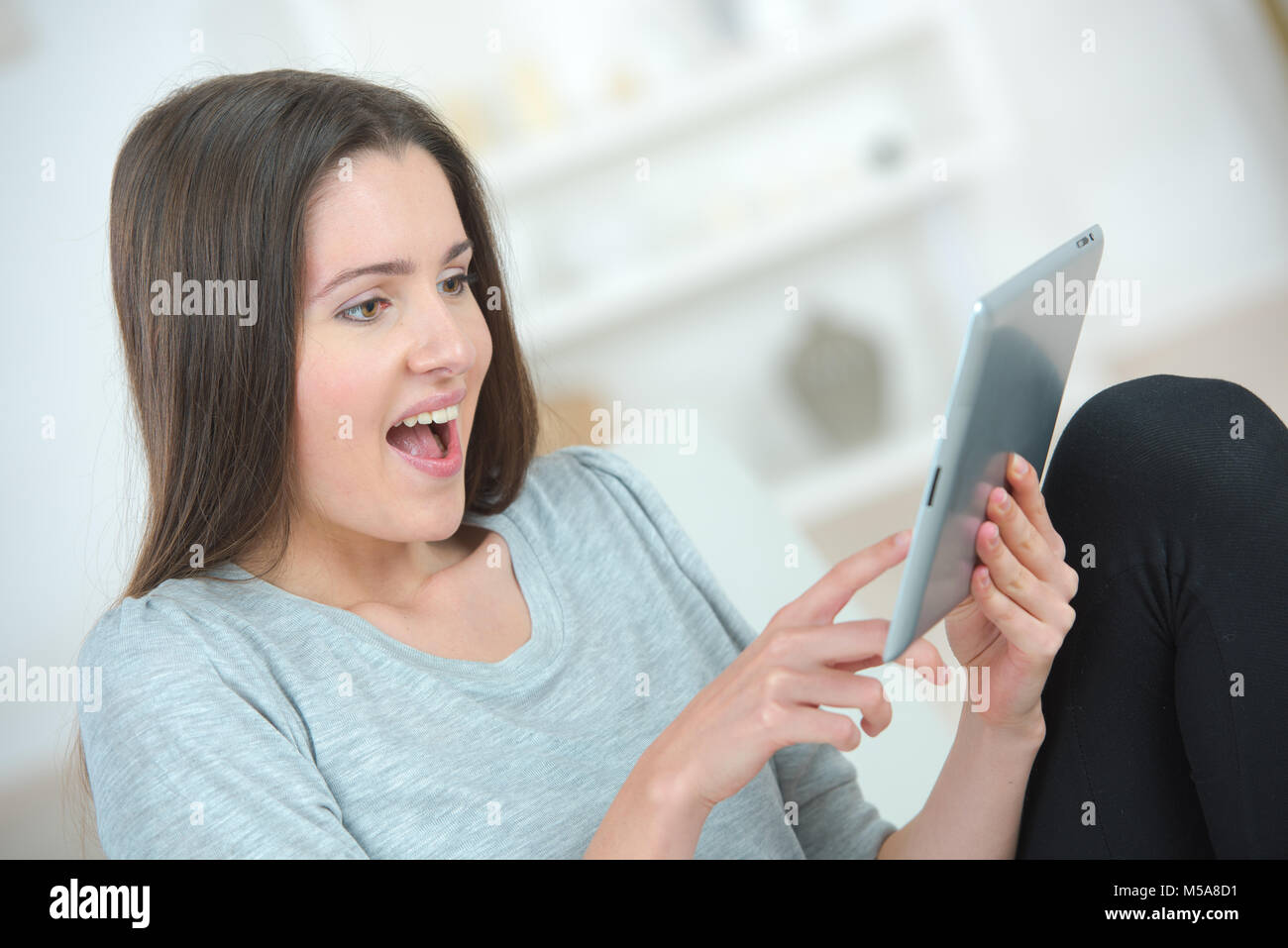 girl using tablet surprised expression on her face Stock Photo - Alamy