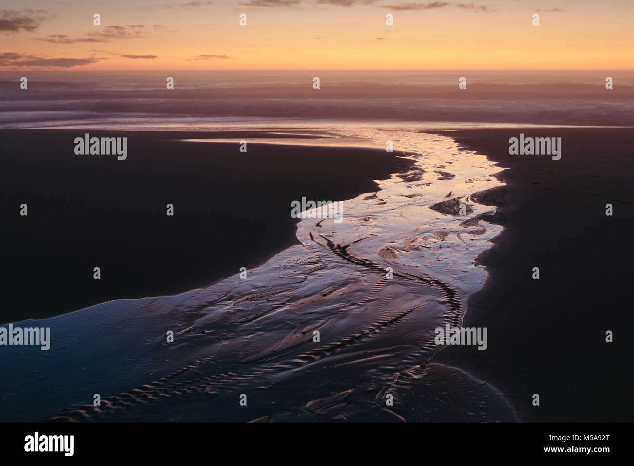 Landscape with stream flowing into ocean surf at dusk Stock Photo - Alamy
