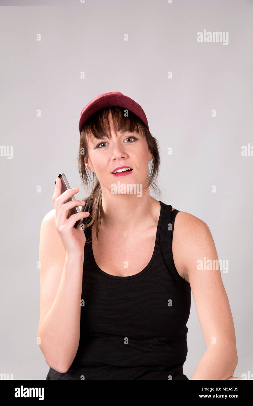 Woman wearing a cap and using a mobile phone Stock Photo - Alamy