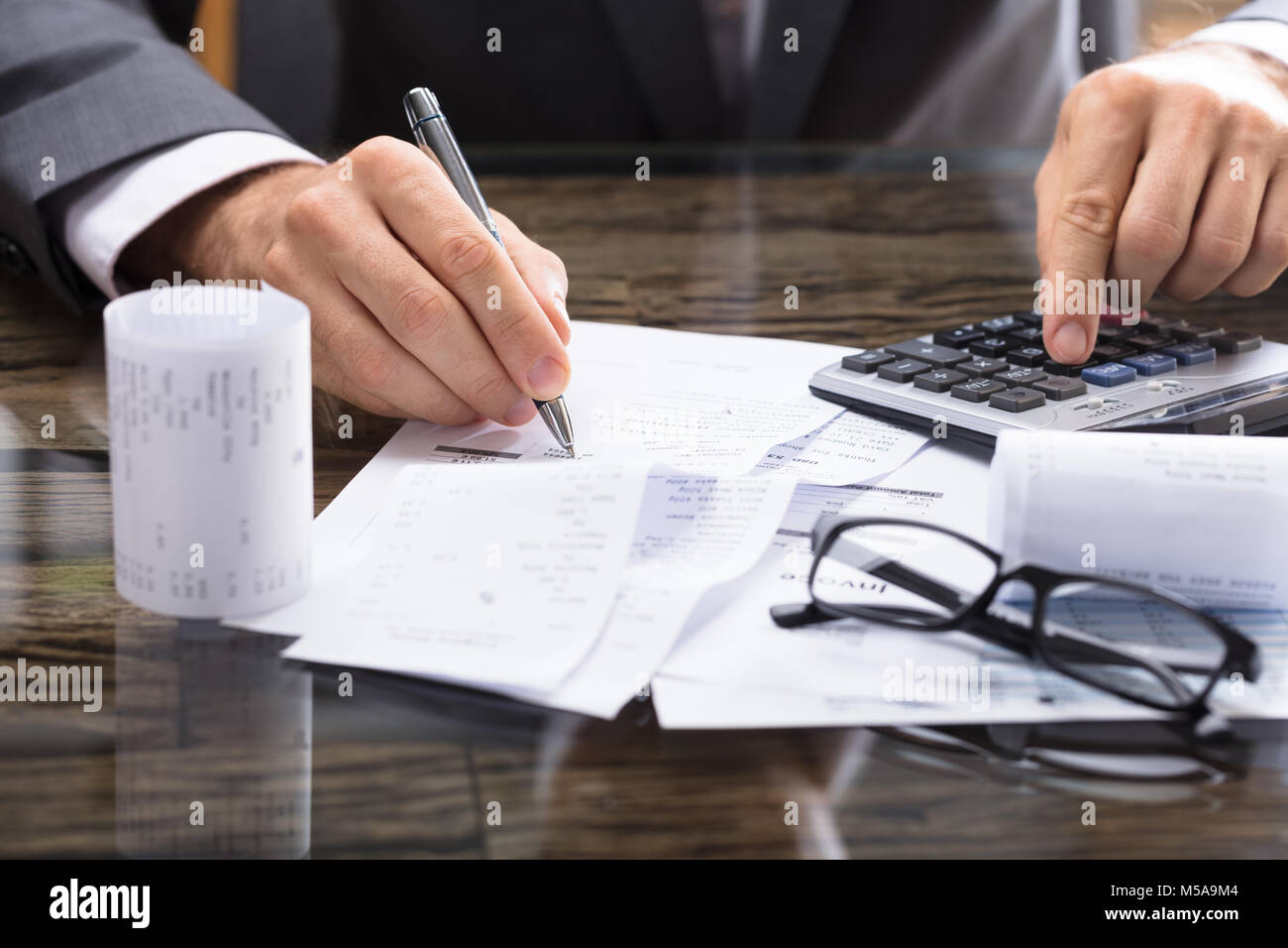 Businessperson's Hand Calculating Receipt With Calculator On Desk In ...