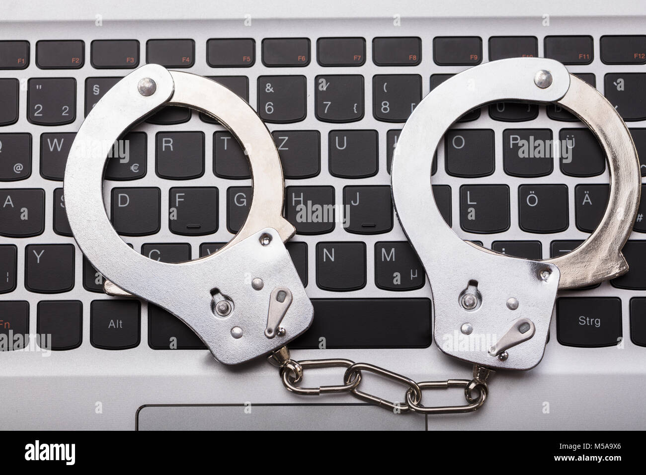 High Angle View Of Handcuffs On Laptop Keyboard Stock Photo - Alamy