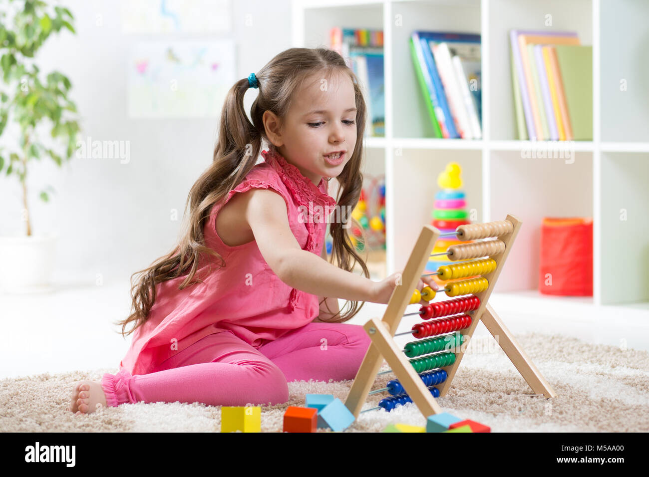 smiling kid girl playing with counter toy Stock Photo - Alamy