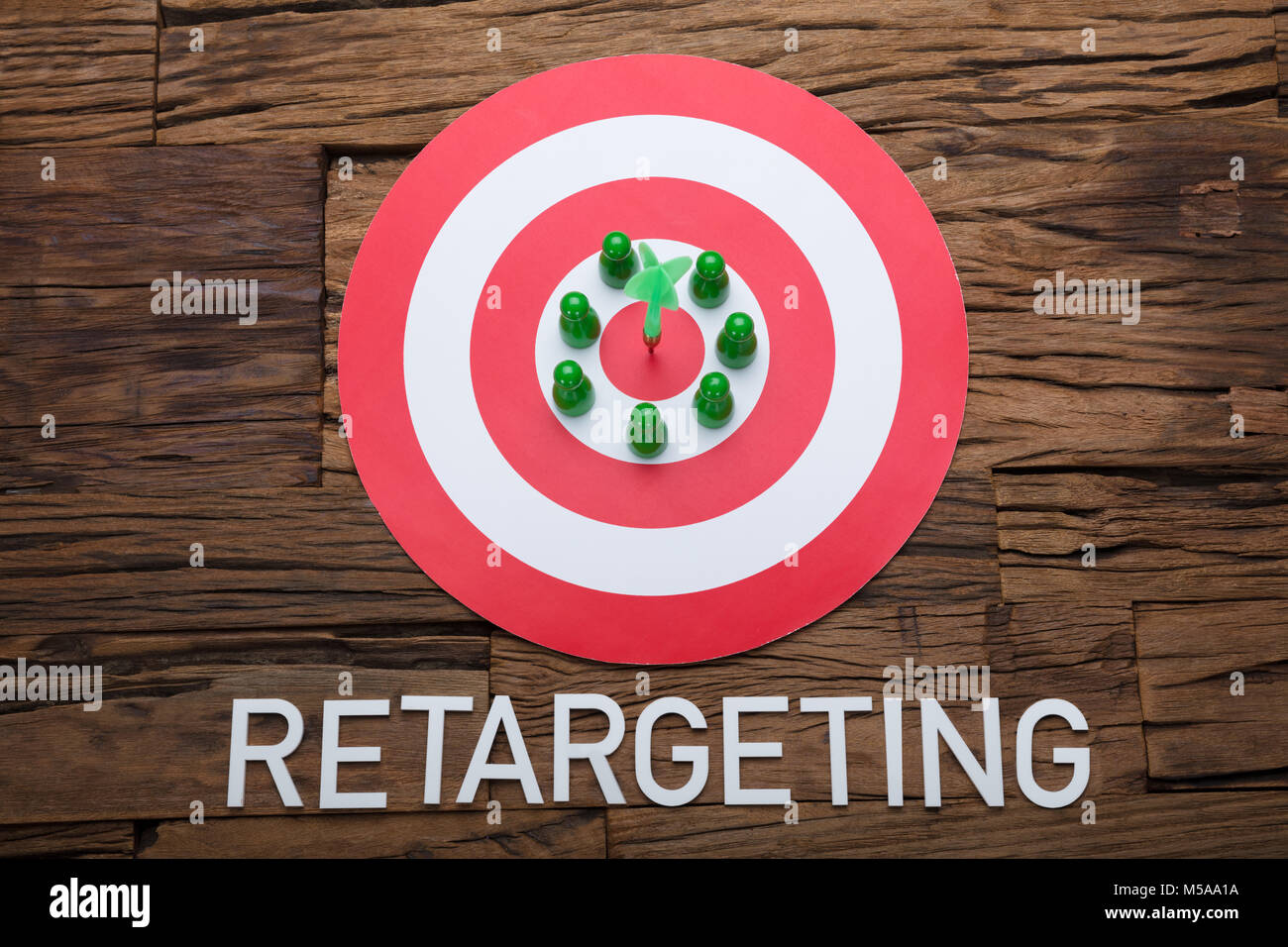 Arrow and pawn figurines on dartboard with retargeting text at wooden ...