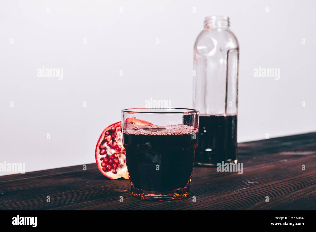 Fresh juice, a cut grenade, a glass and a bottle on the table Stock ...
