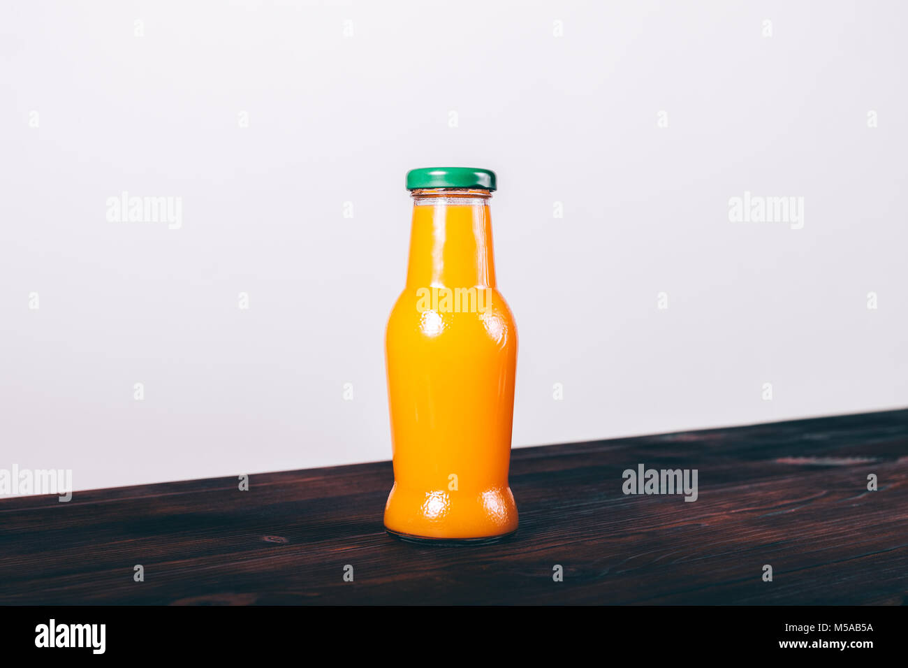 Small bottle of orange juice with green cap on white background Stock ...