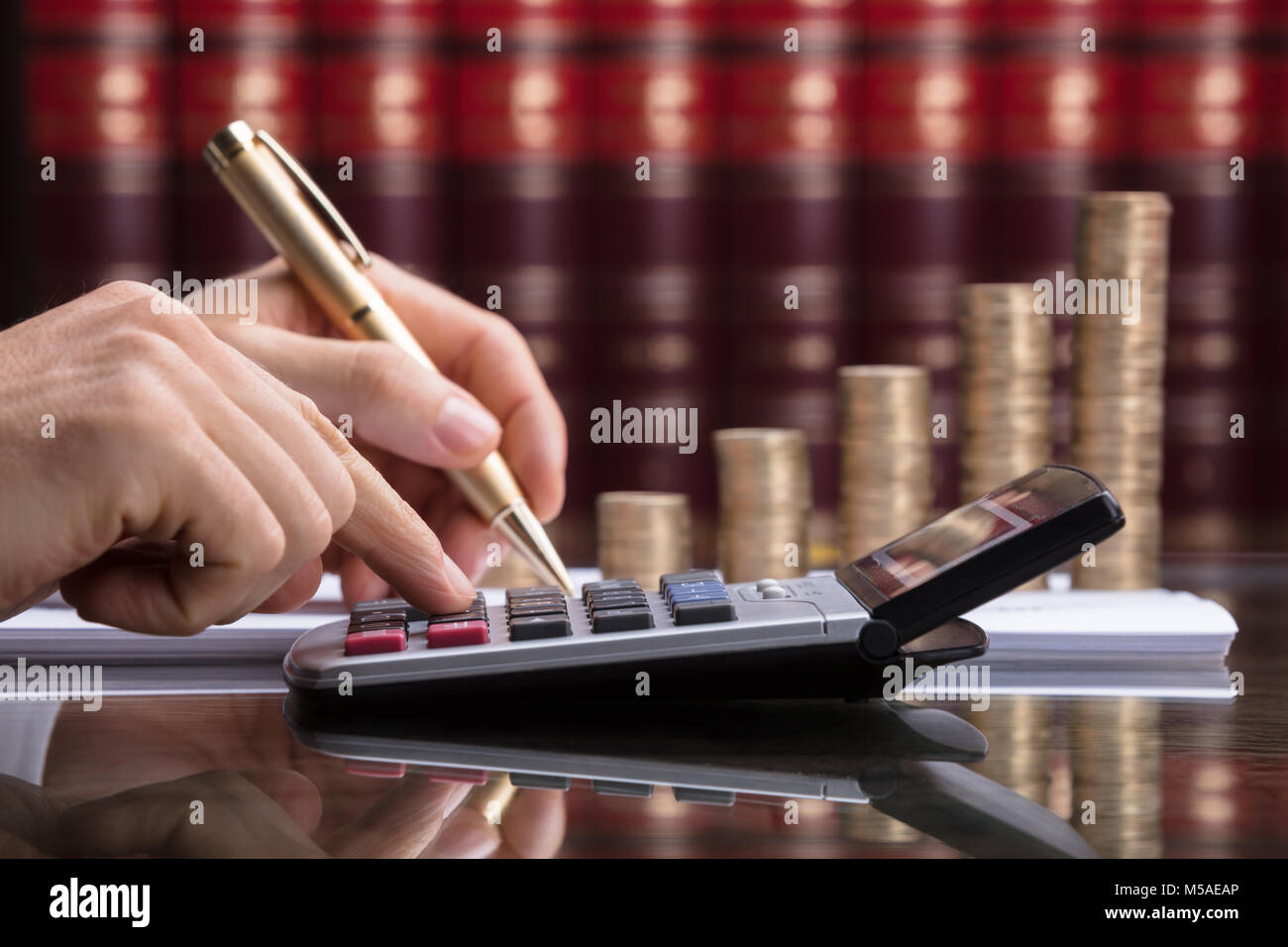 Close-up Of A Person Calculating Invoice In Front Of Stacked Coins ...