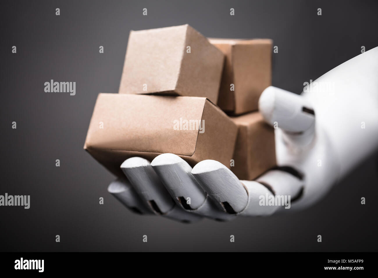 Close-up Of A Robot's Hand Holding Cardboard Boxes On Grey Background ...