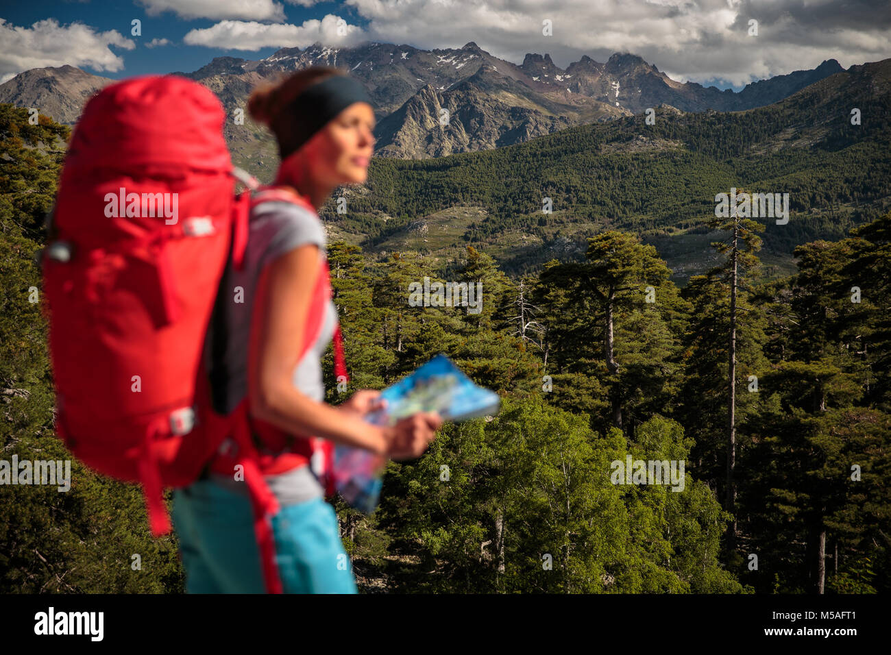 Pretty, female hiker in high mountains packing her backpack Stock Photo ...
