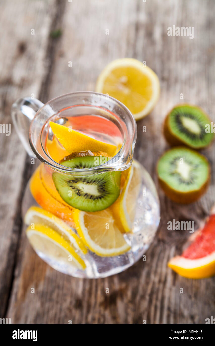 Refreshing ice cold water with lemon, kiwi and grapefruit on a wooden background. Concept of ...