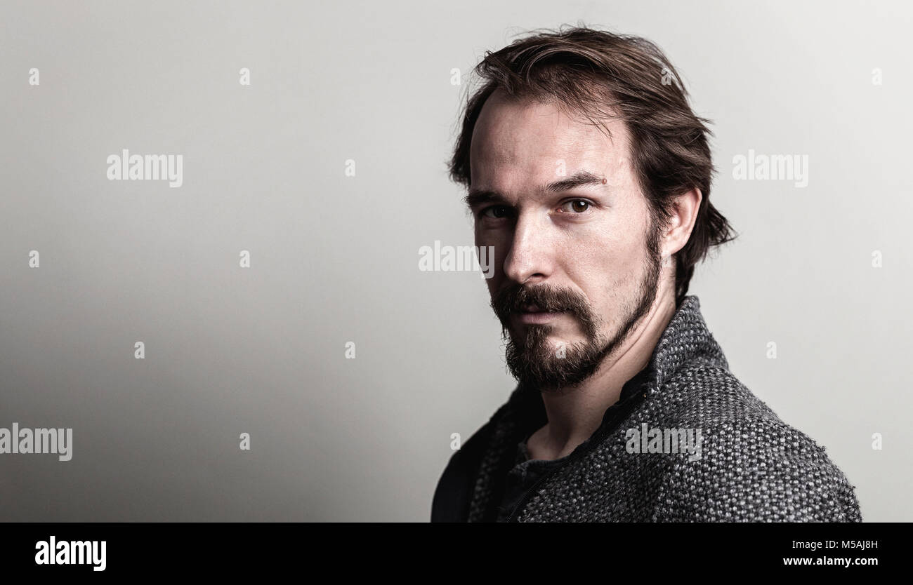 Portrait of a handsome serious and casual young man against grey ...