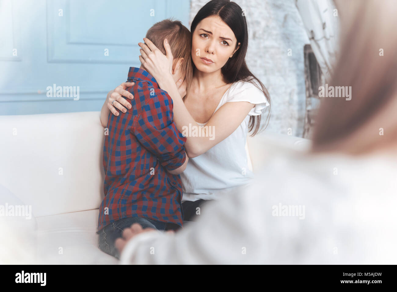 Worried mother calming her son in psychologist office Stock Photo - Alamy