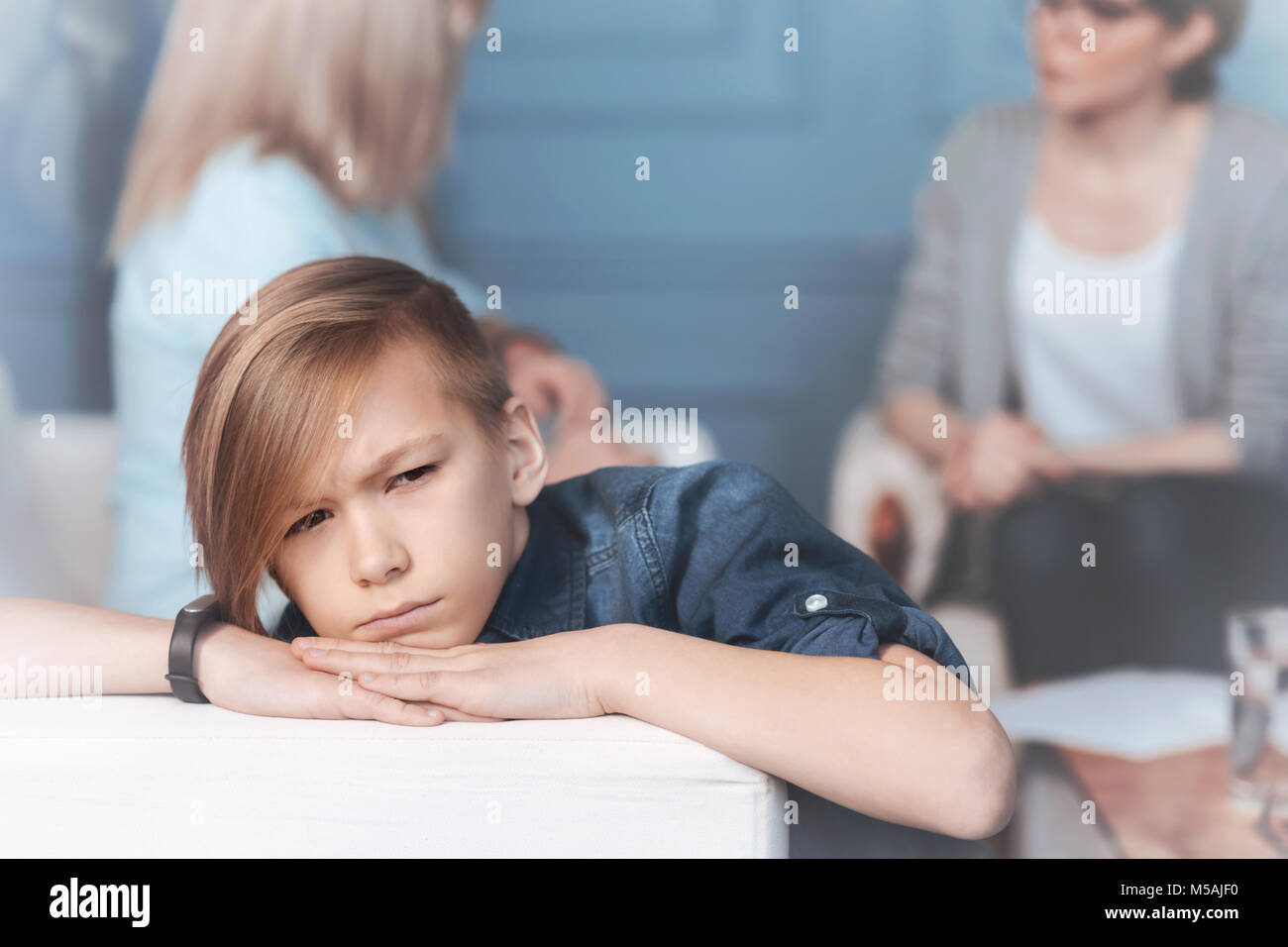 Grumpy child relaxing on sofa in psychologist office Stock Photo - Alamy
