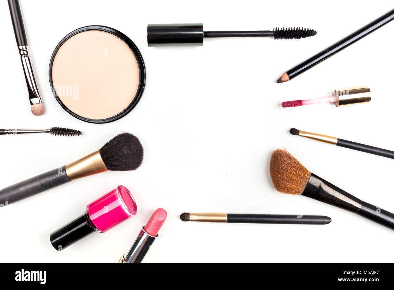 Makeup brushes, pencil, lipstick, and other objects, forming a frame on ...