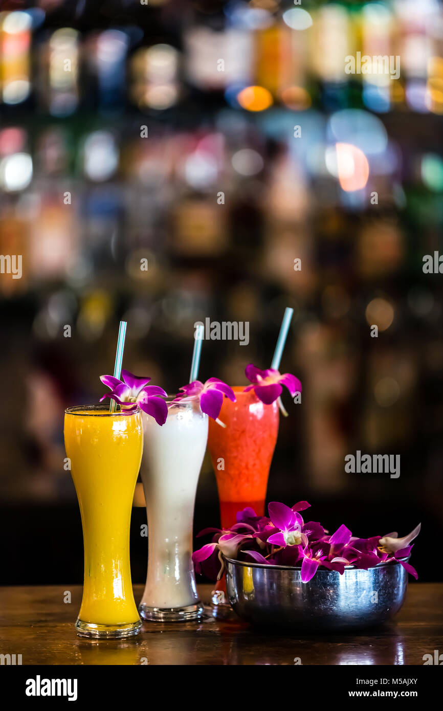 Vertical composition with 3 yellow, white, red cocktails and orchid ...