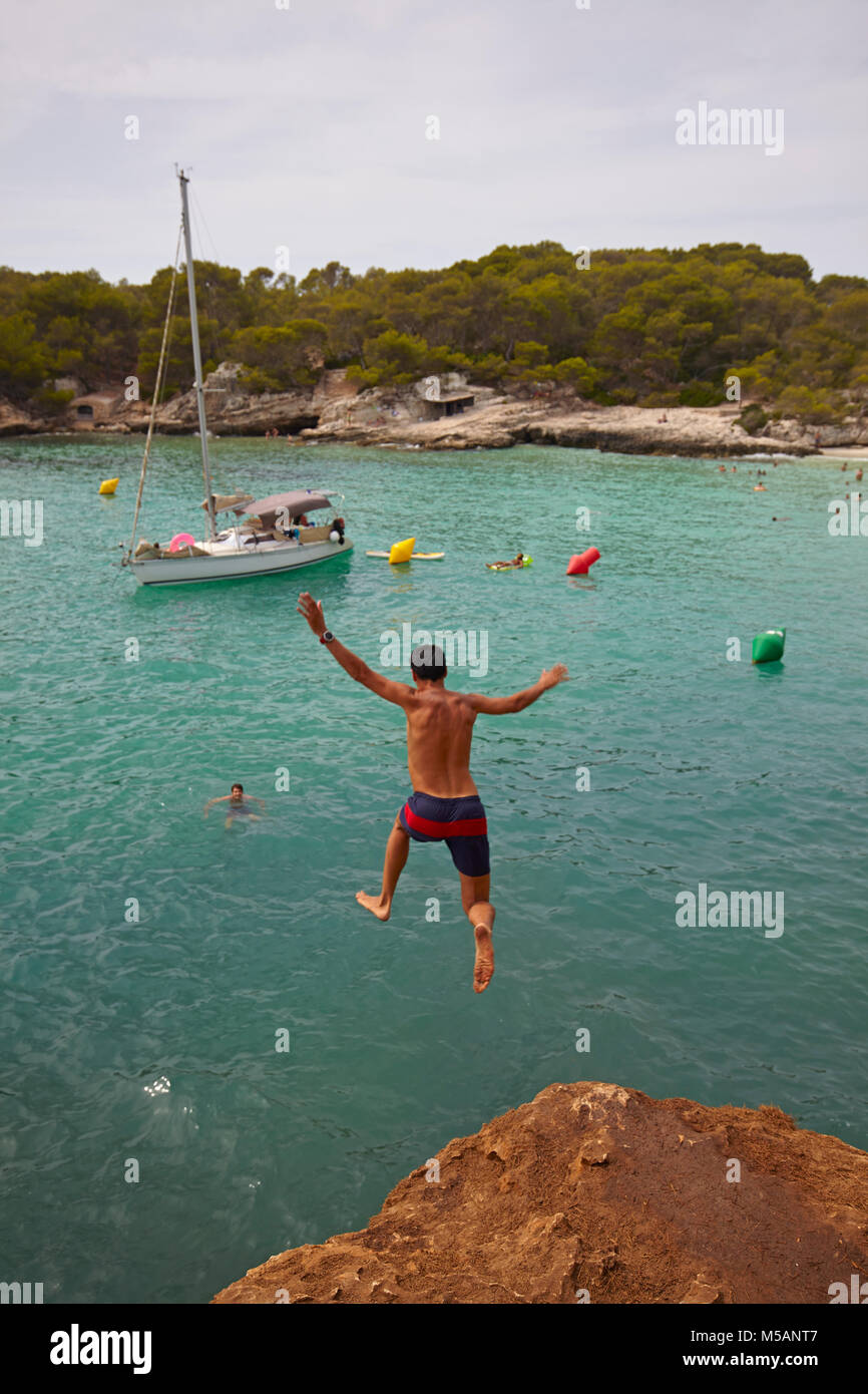 Young boy diving from rocks in Cala en Turqueta, Menorca,Balearic ...