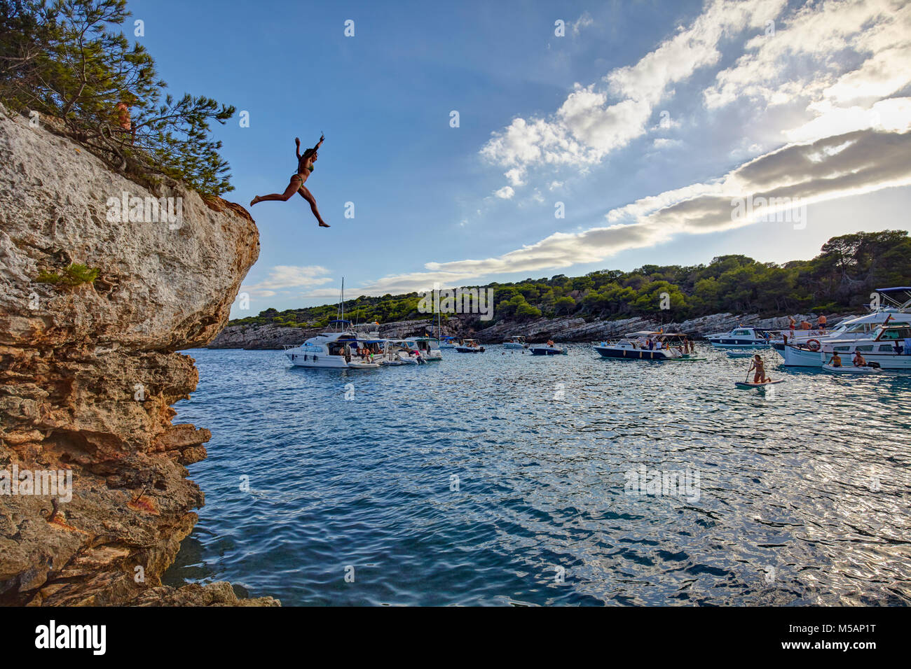 Girl diving from rocks in Cala en Turqueta, Menorca,Balearic Islands ...