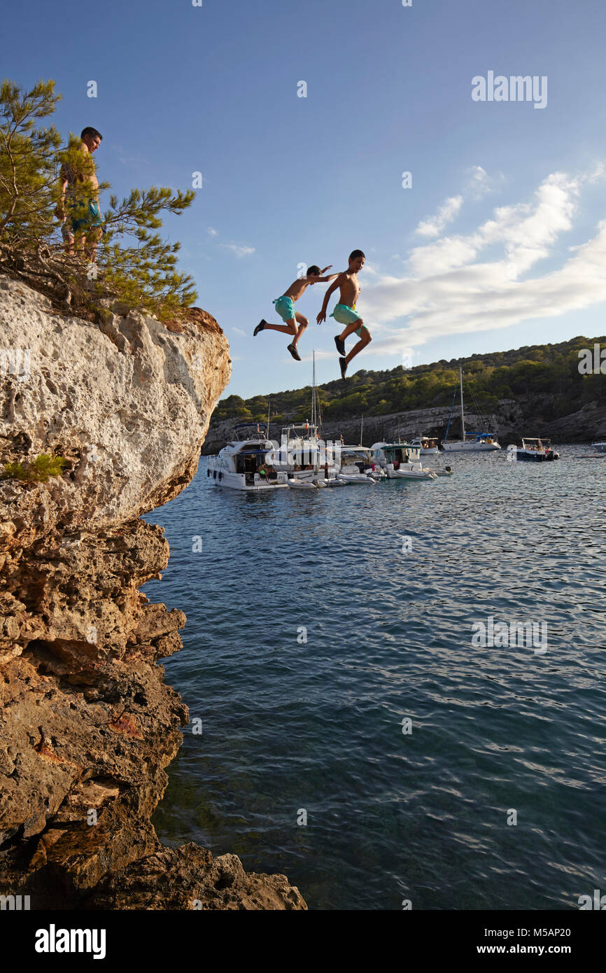Boys diving from rocks in Cala en Turqueta, Menorca,Balearic Islands ...