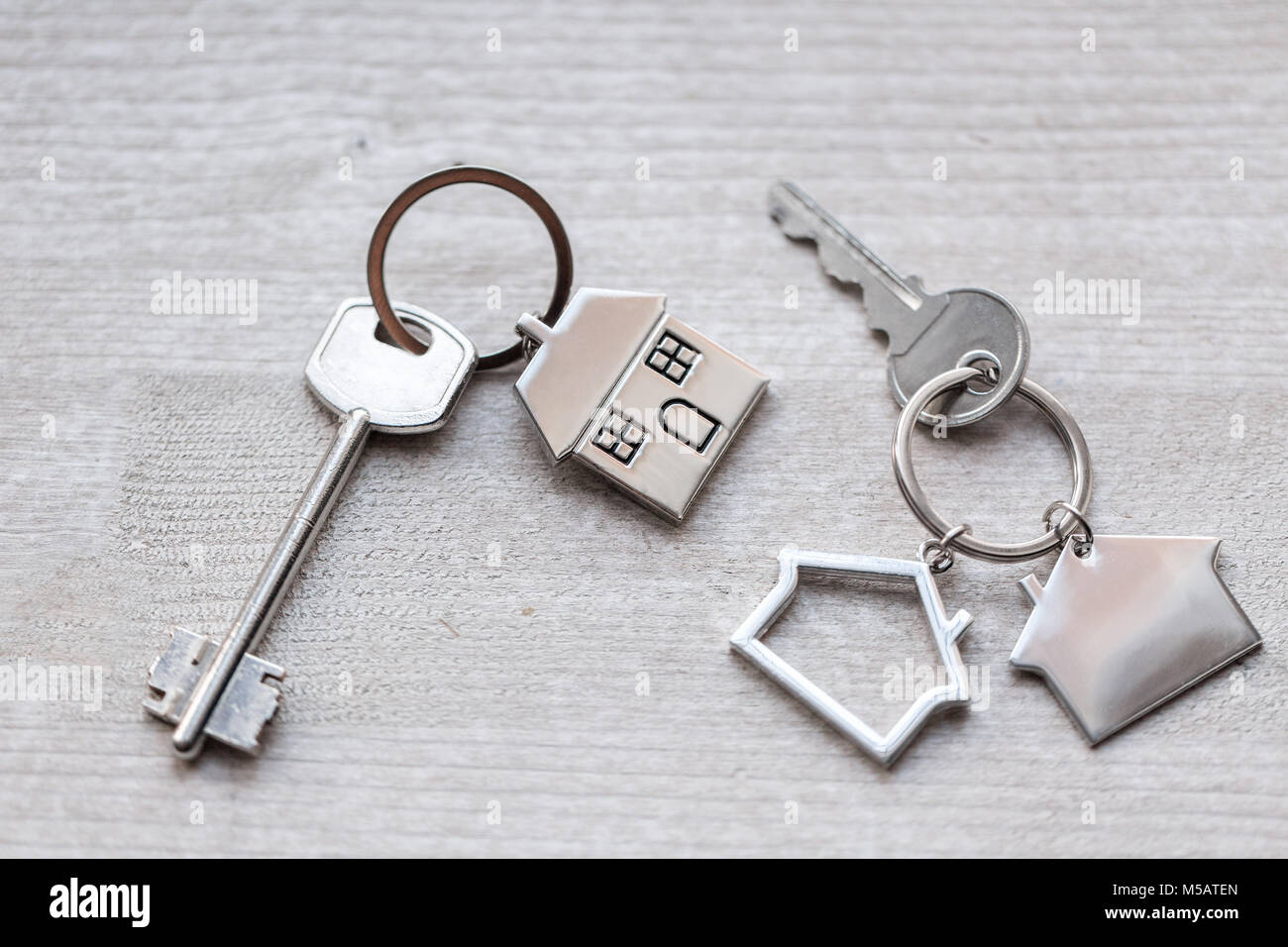 Two House key and keychain in the form of homes lies on wooden boards ...