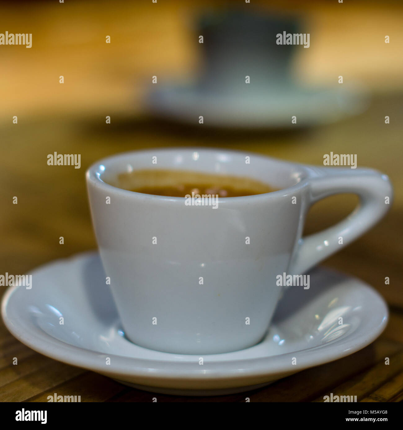 Two cups of espresso coffee set on wooden table to illustrate de ...