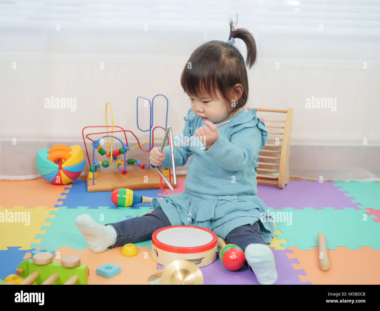 baby girl play triangle at home Stock Photo - Alamy