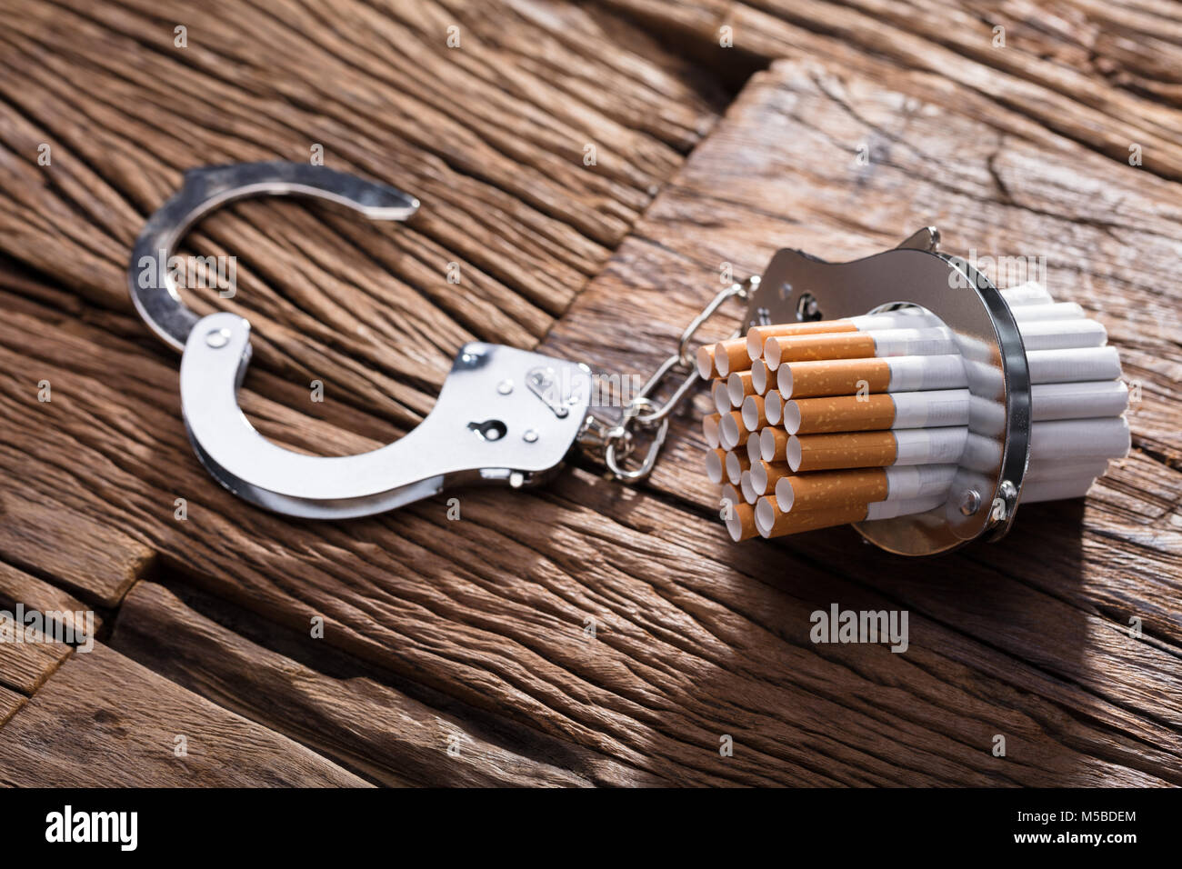 Elevated View Of Cigarettes And Handcuff On Wooden Desk Stock Photo - Alamy
