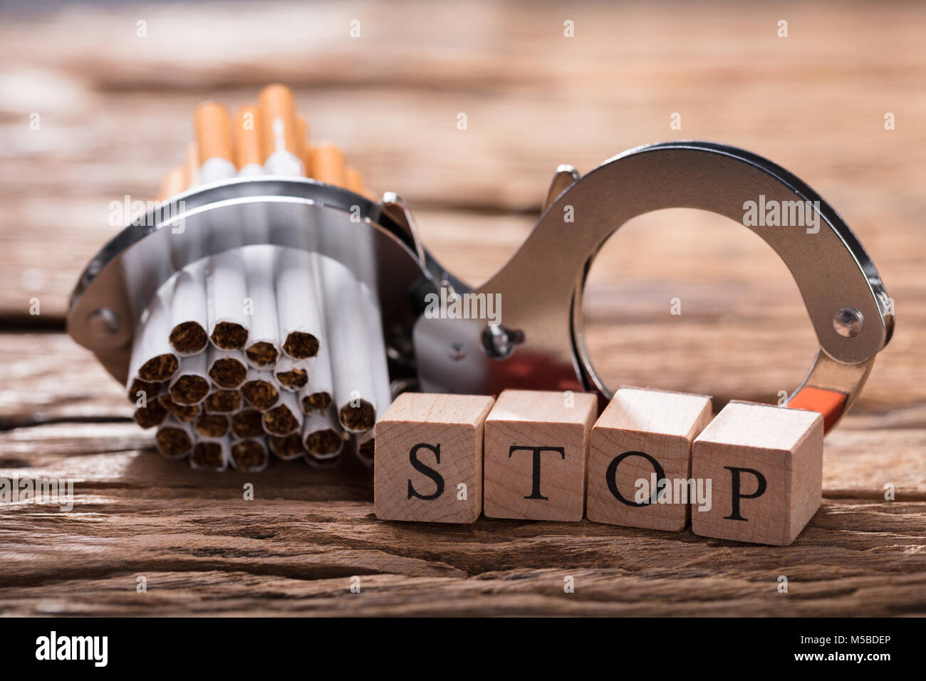 Close-up Of Cigarettes And Handcuff With Wooden Blocks Showing Stop ...