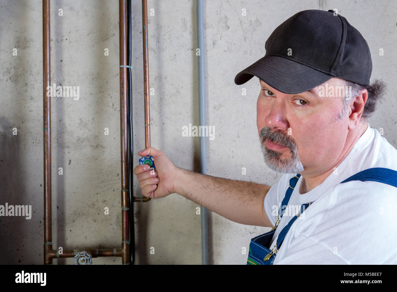 Plumber or homeowner winterising a house turning on or off a valve on a ...