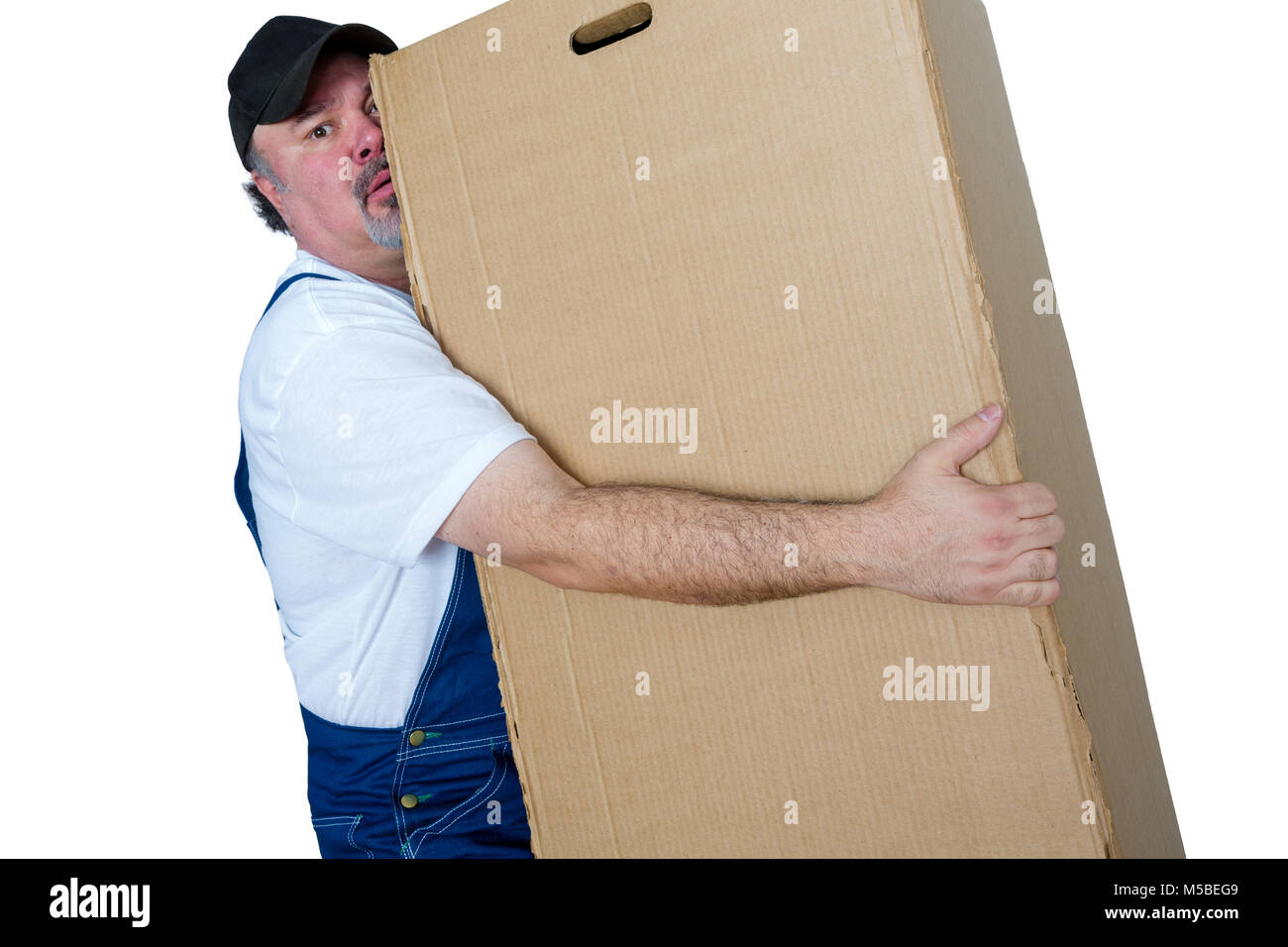 Delivery man carrying heavy cardboard box against white background ...