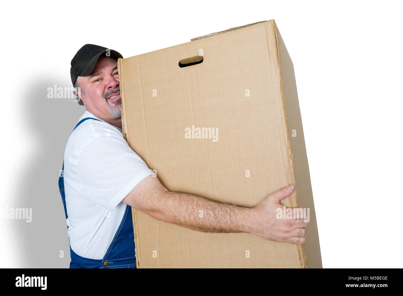 Delivery man lifting large heavy cardboard box against white background ...