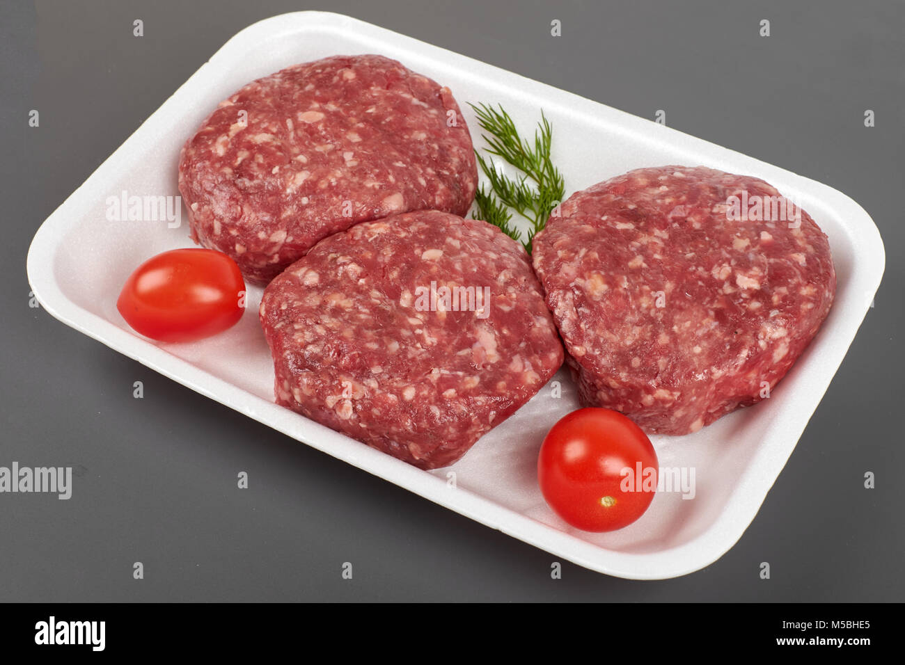 Tray with raw beef burgers isolated on gray background Stock Photo - Alamy