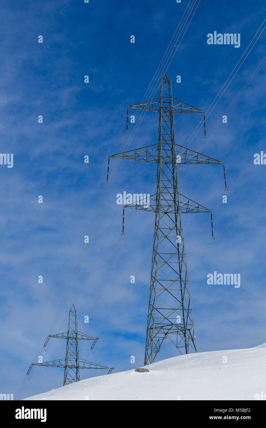 close view two electricity pylons in winter, snow, sunny blue cloudy ...