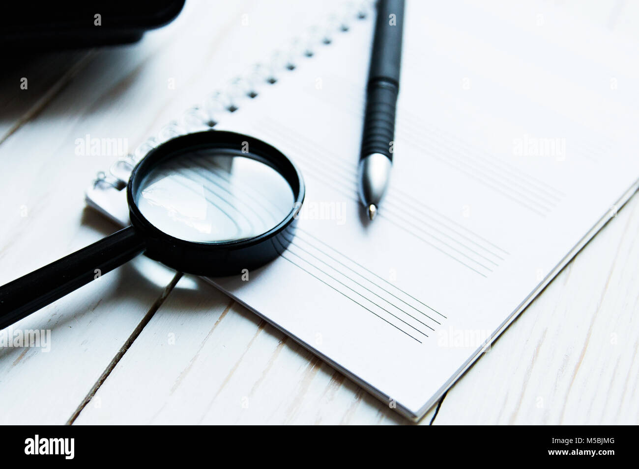 Magnifier on a laptop, notebook and pen Stock Photo - Alamy