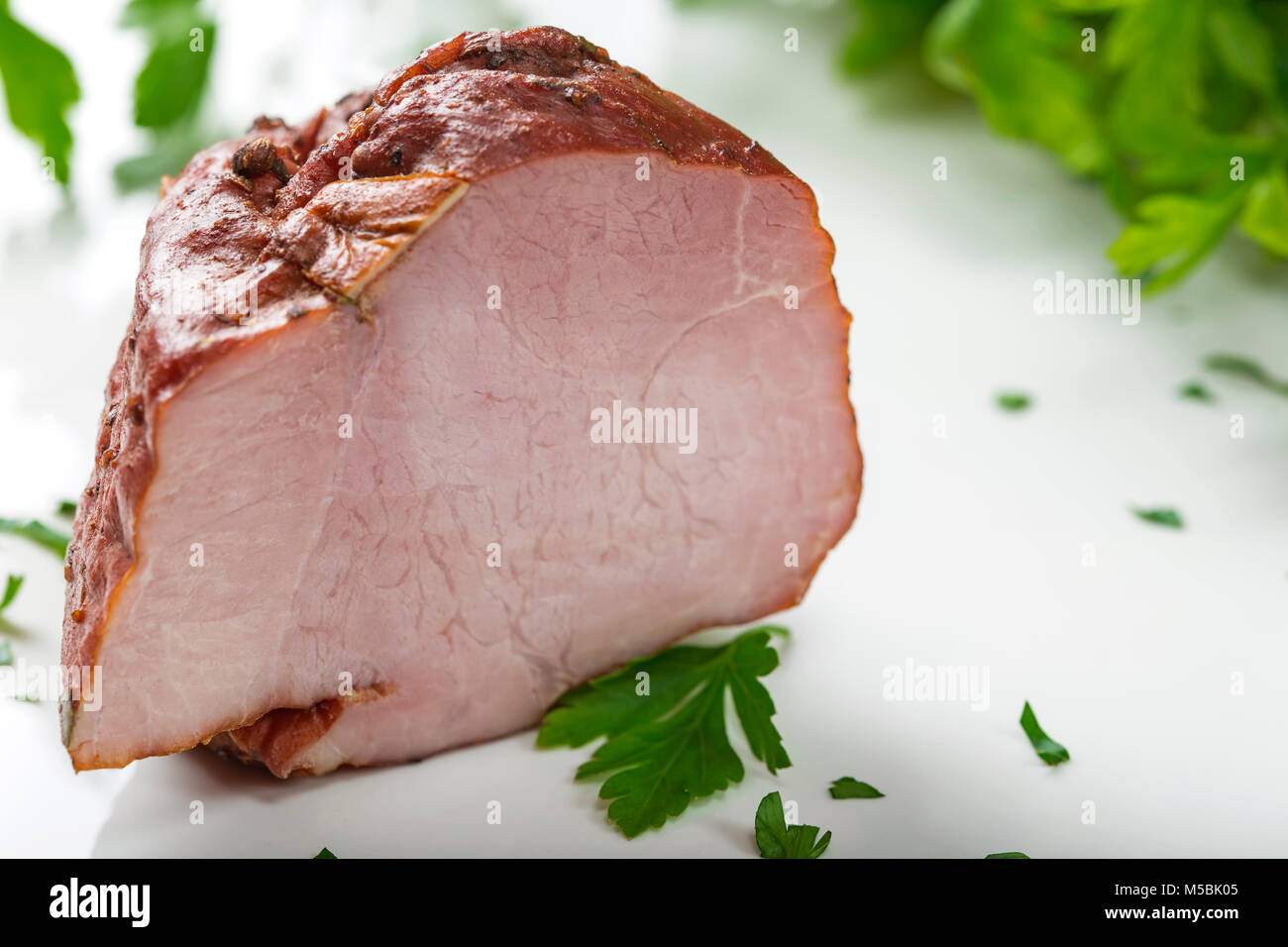 Piece of pork smoked ham on plate with herbs Stock Photo - Alamy