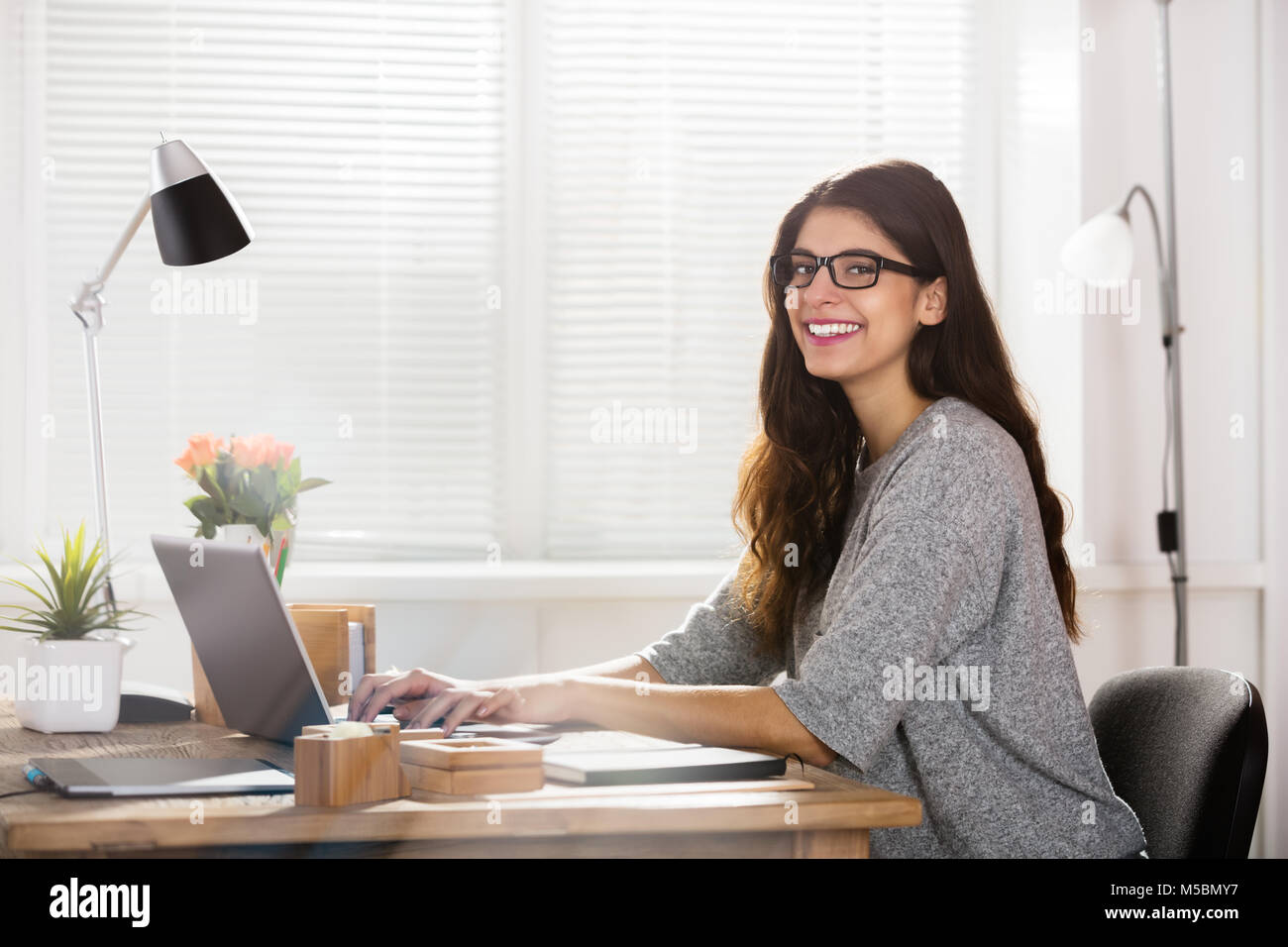 Portrait Of A Smiling Young Woman At Workplace In Office Stock Photo ...