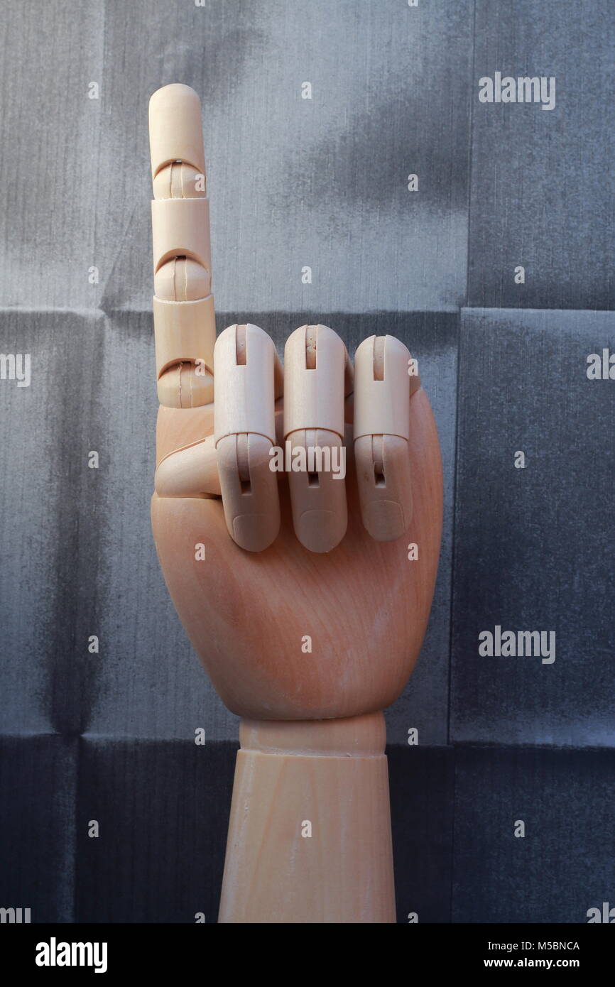 Wooden hand with a raised finger with a vintage painted paper ...