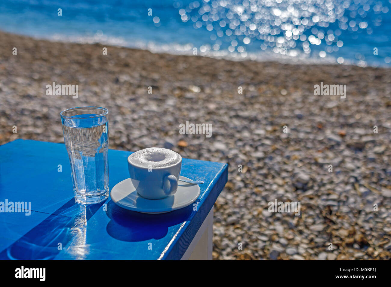 Cup of Coffee or Cappuccino on the blue wooden table at the beach ...