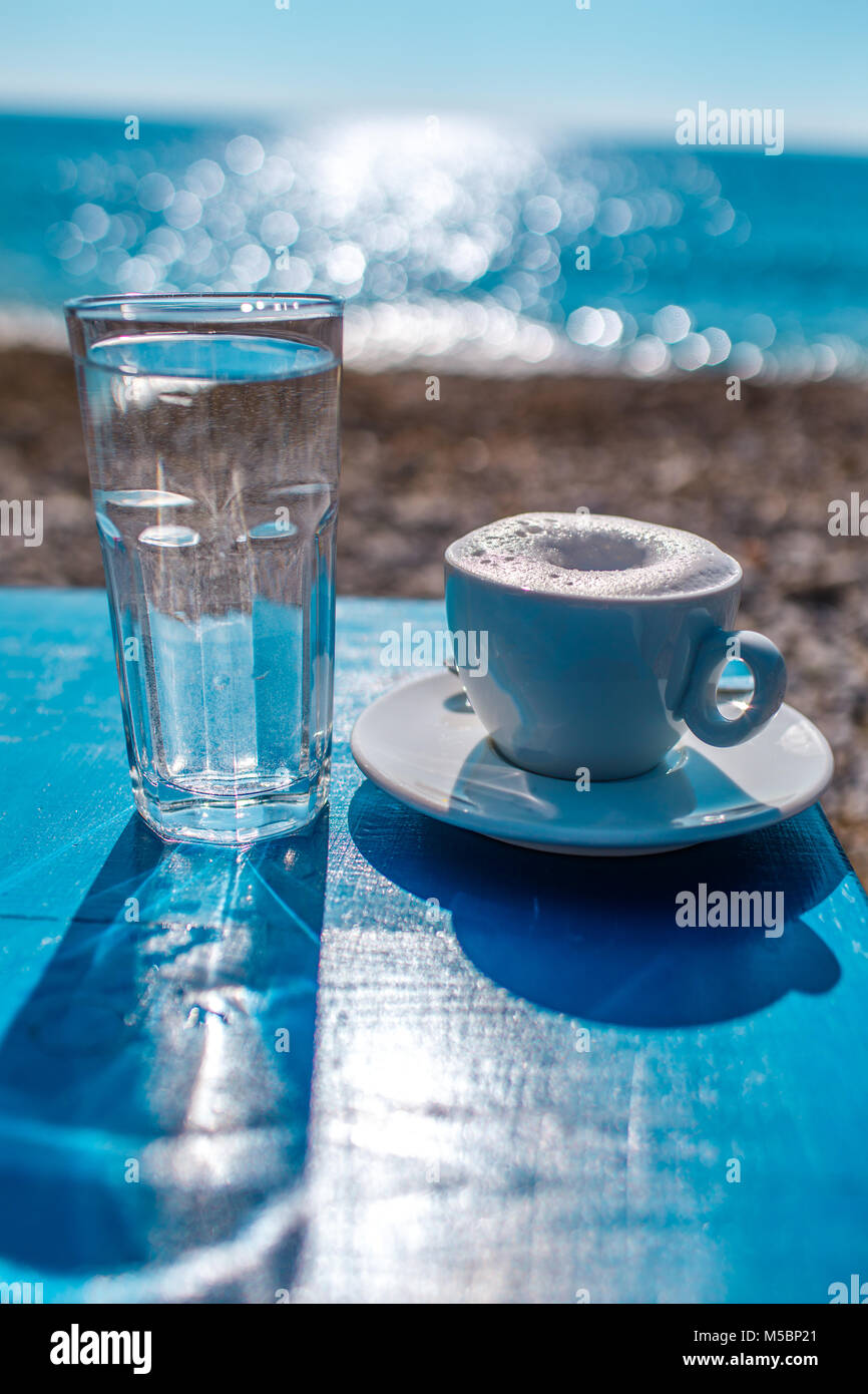 Cup of Coffee or Cappuccino on the blue wooden table at the beach ...