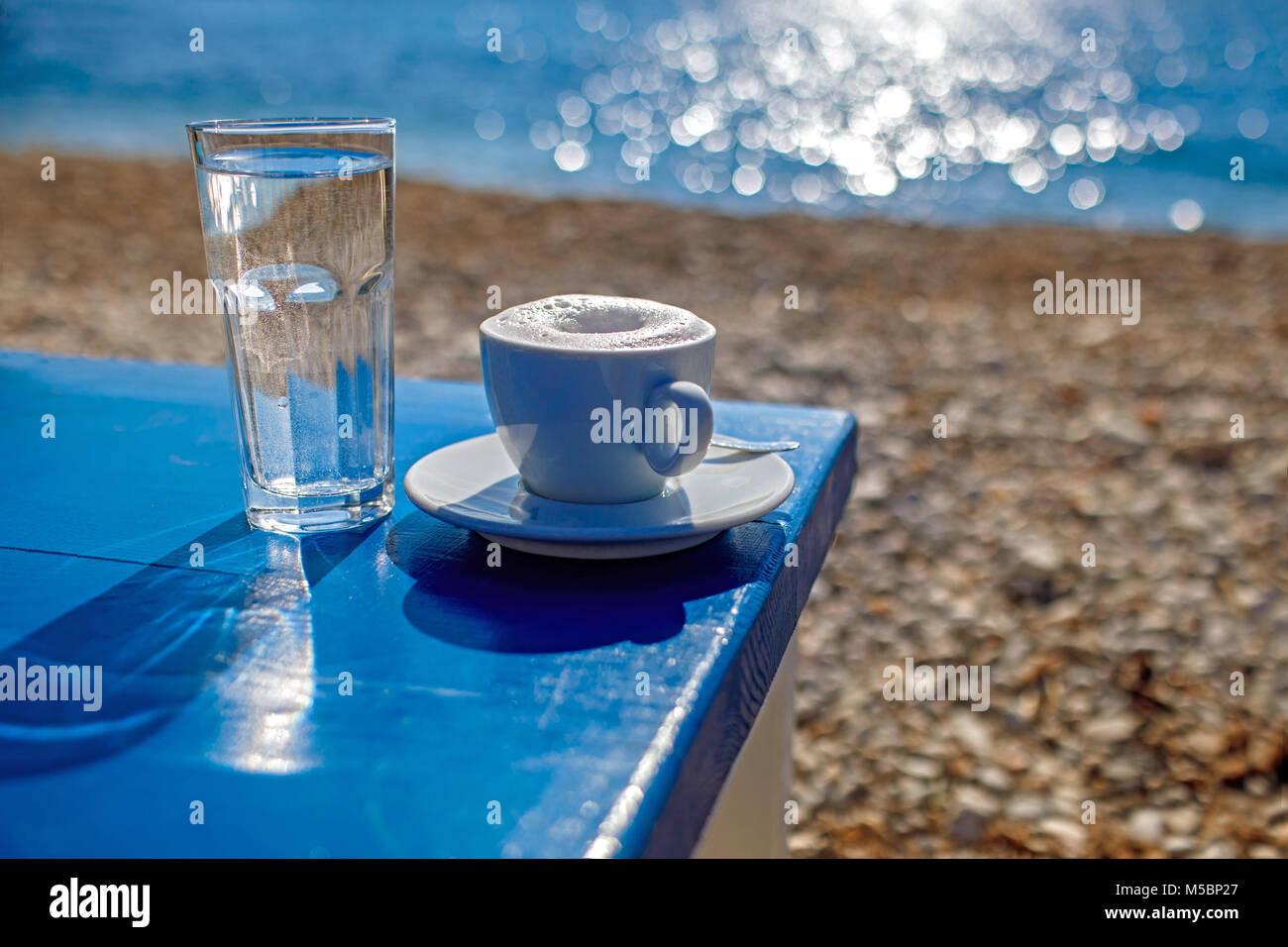 Cup of Coffee or Cappuccino on the blue wooden table at the beach ...