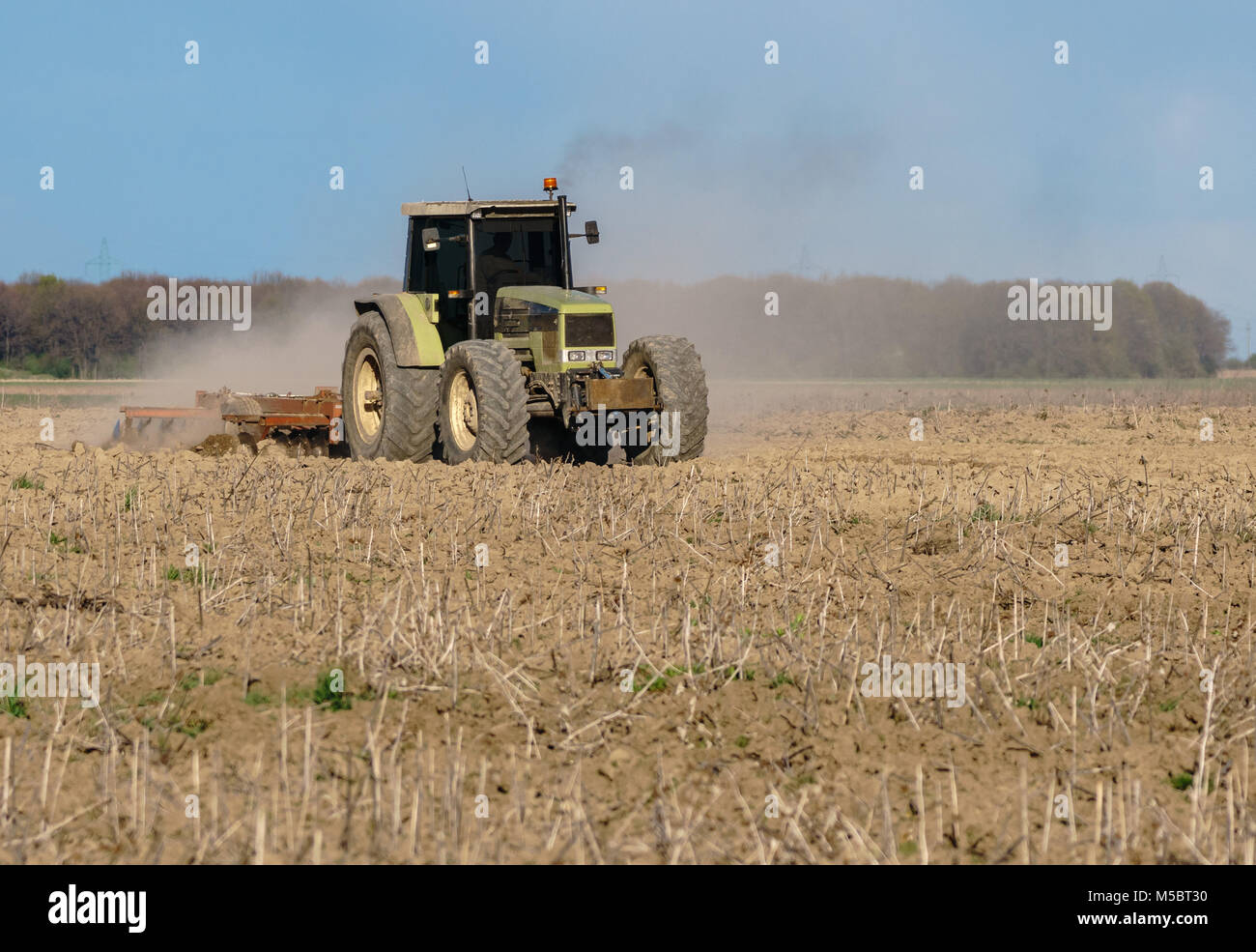 Tractor harrowing ploughed land in a spring day Stock Photo - Alamy