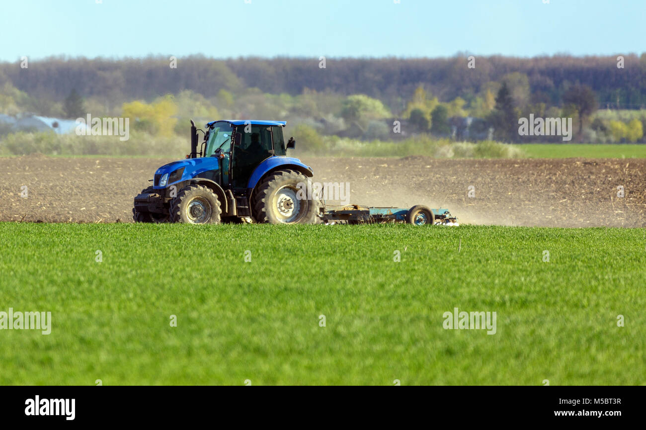 Tractor harrowing ploughed land in a spring day Stock Photo - Alamy