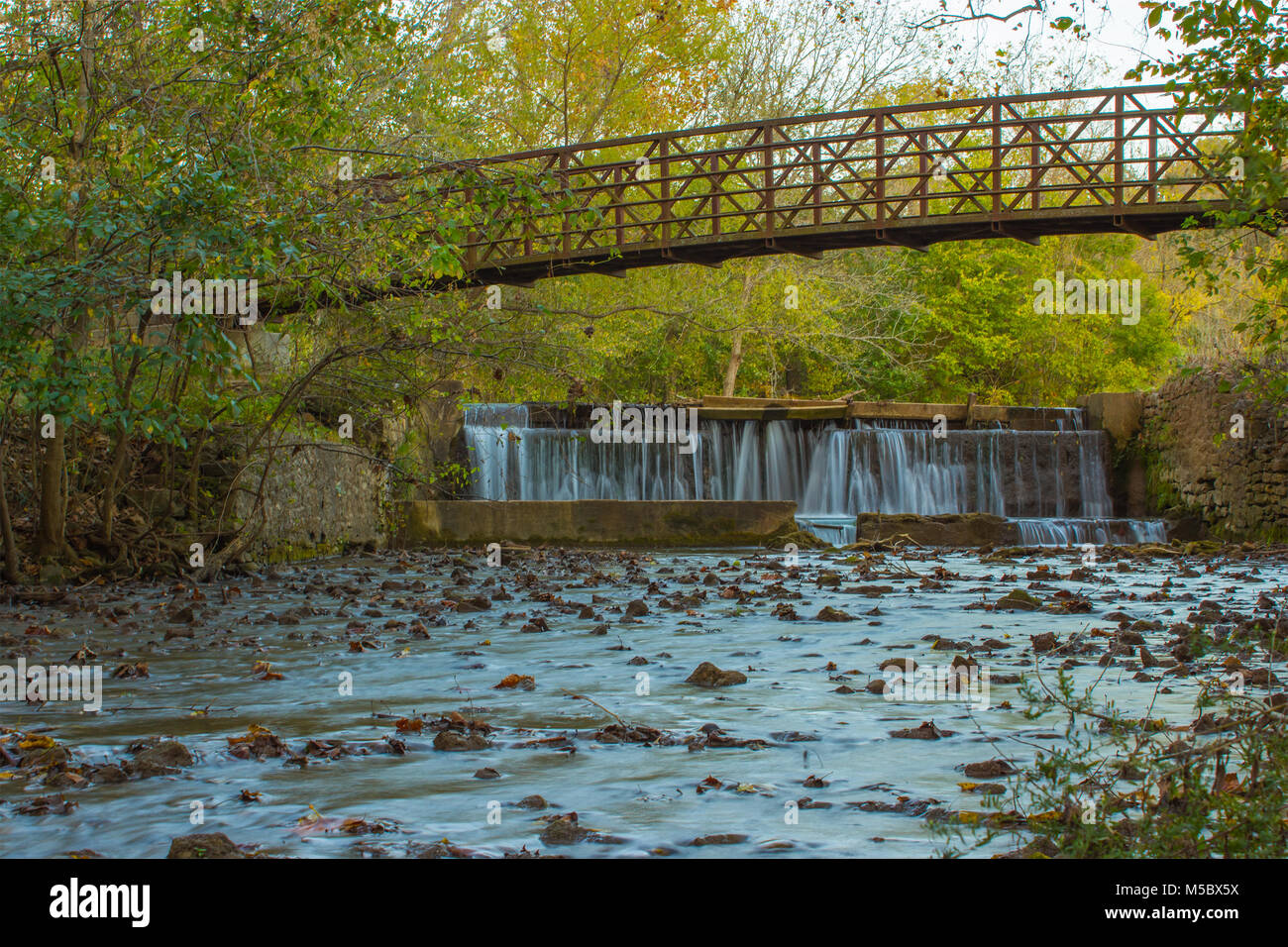Bridge extending over a low running river starting at a dam Stock Photo ...