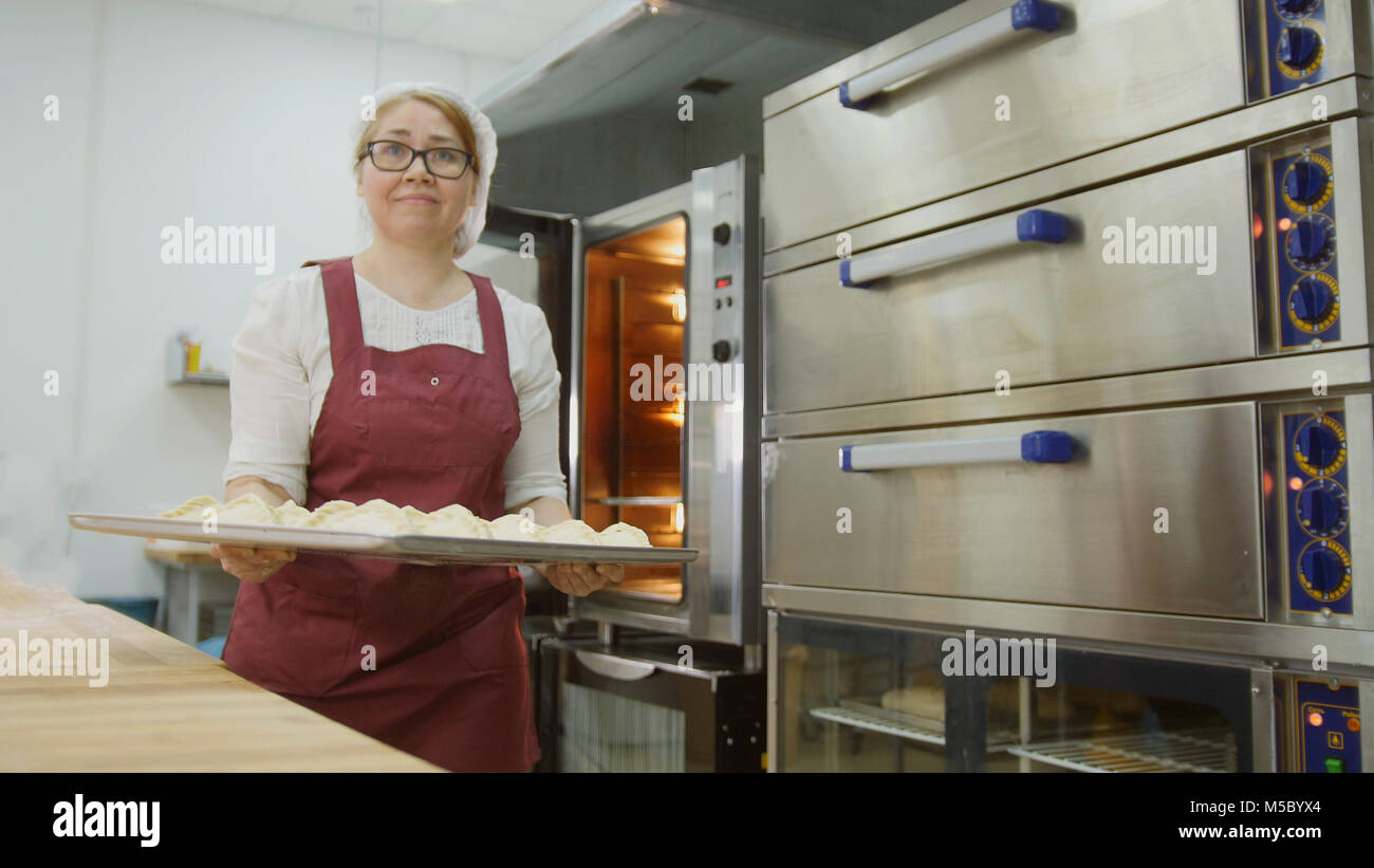 Woman puts raw meat pies in the stove Stock Photo - Alamy
