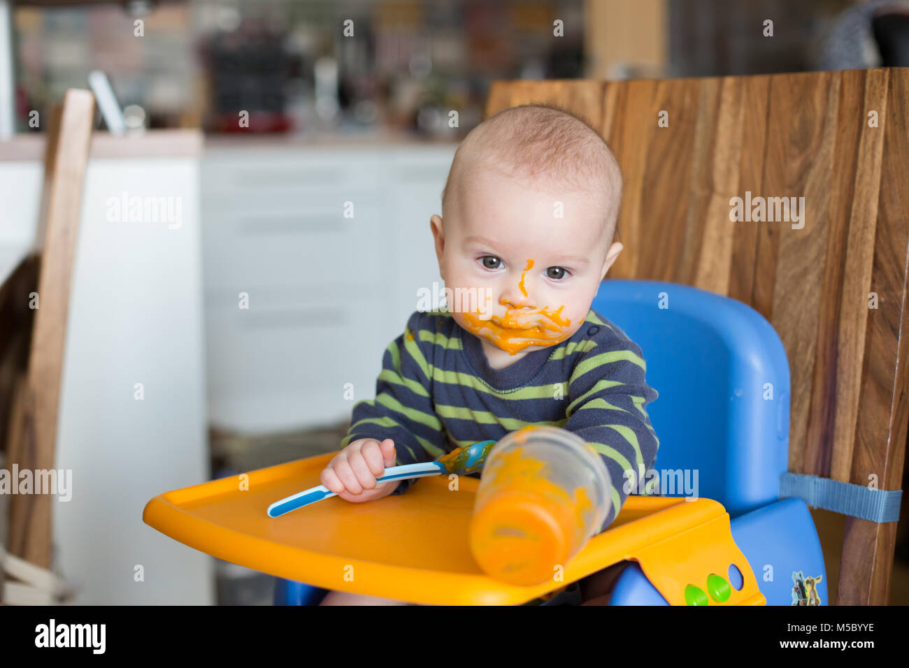 Little baby boy, eating mashed food for the first time in his life ...