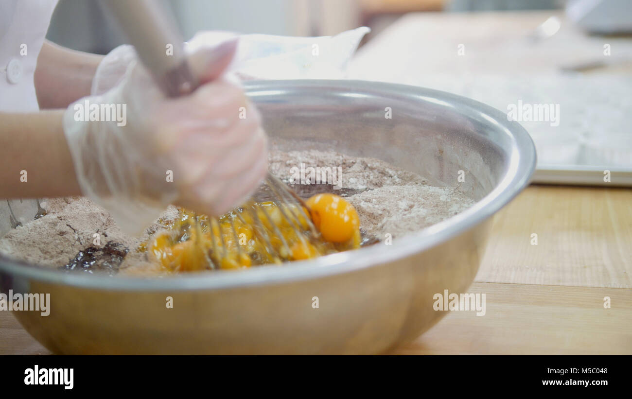 Baker in bakery mixes egg and flour Stock Photo - Alamy